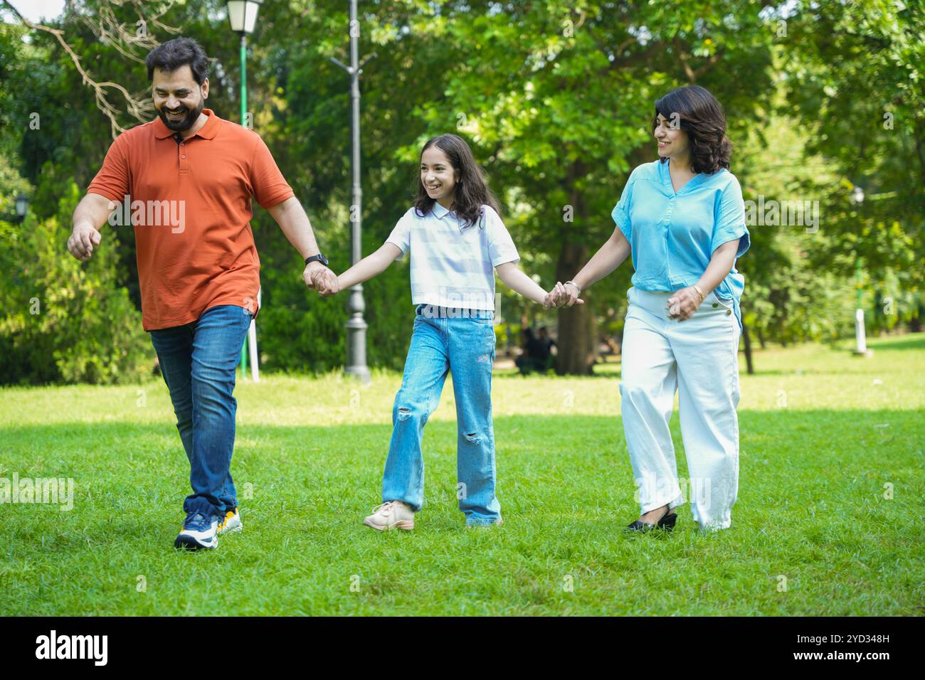Happy indian family holding hands walking in summer park, Playful ...