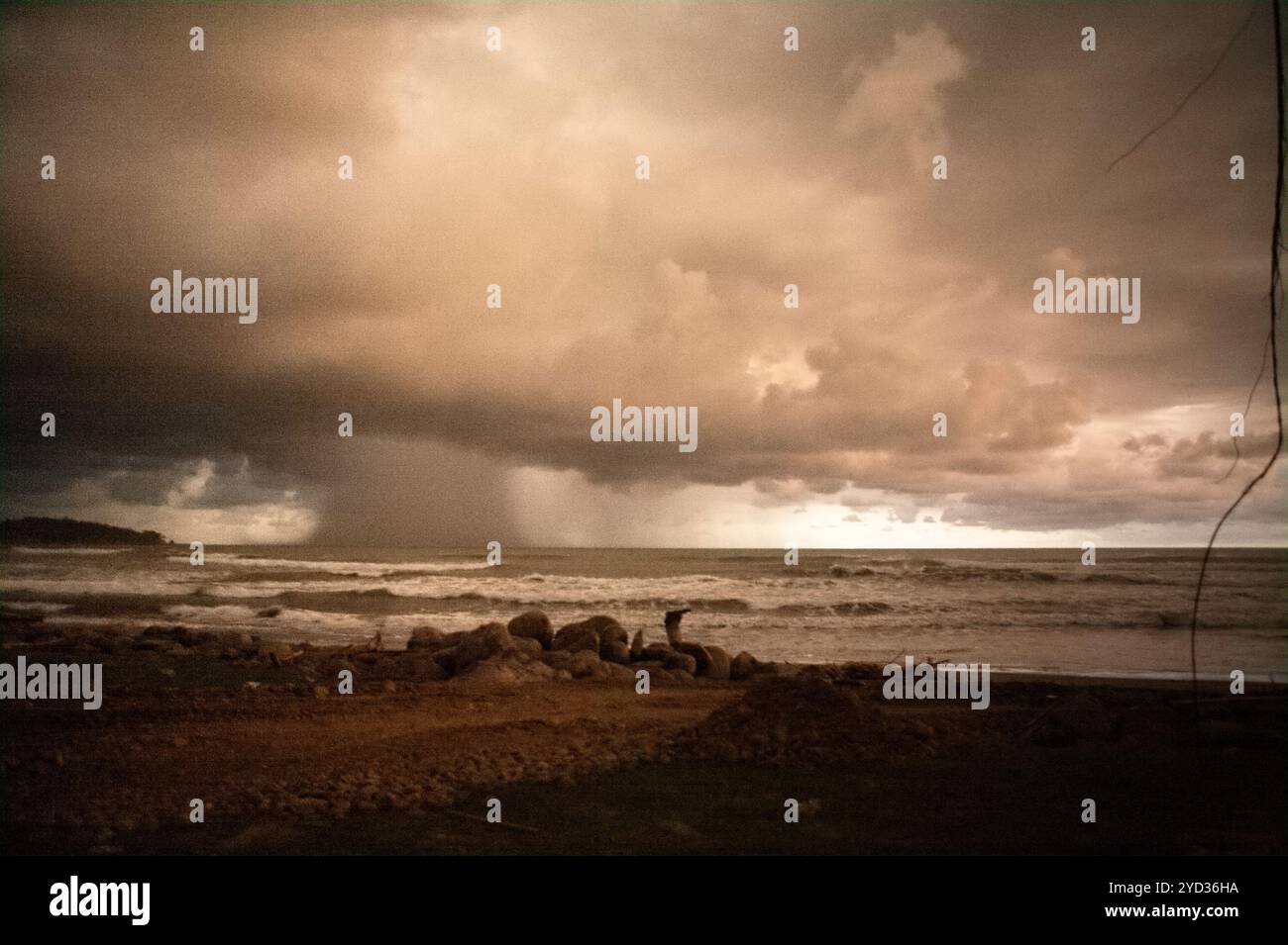 Stormy rainclouds and rainfall over Indian Ocean are seen from a beach ...
