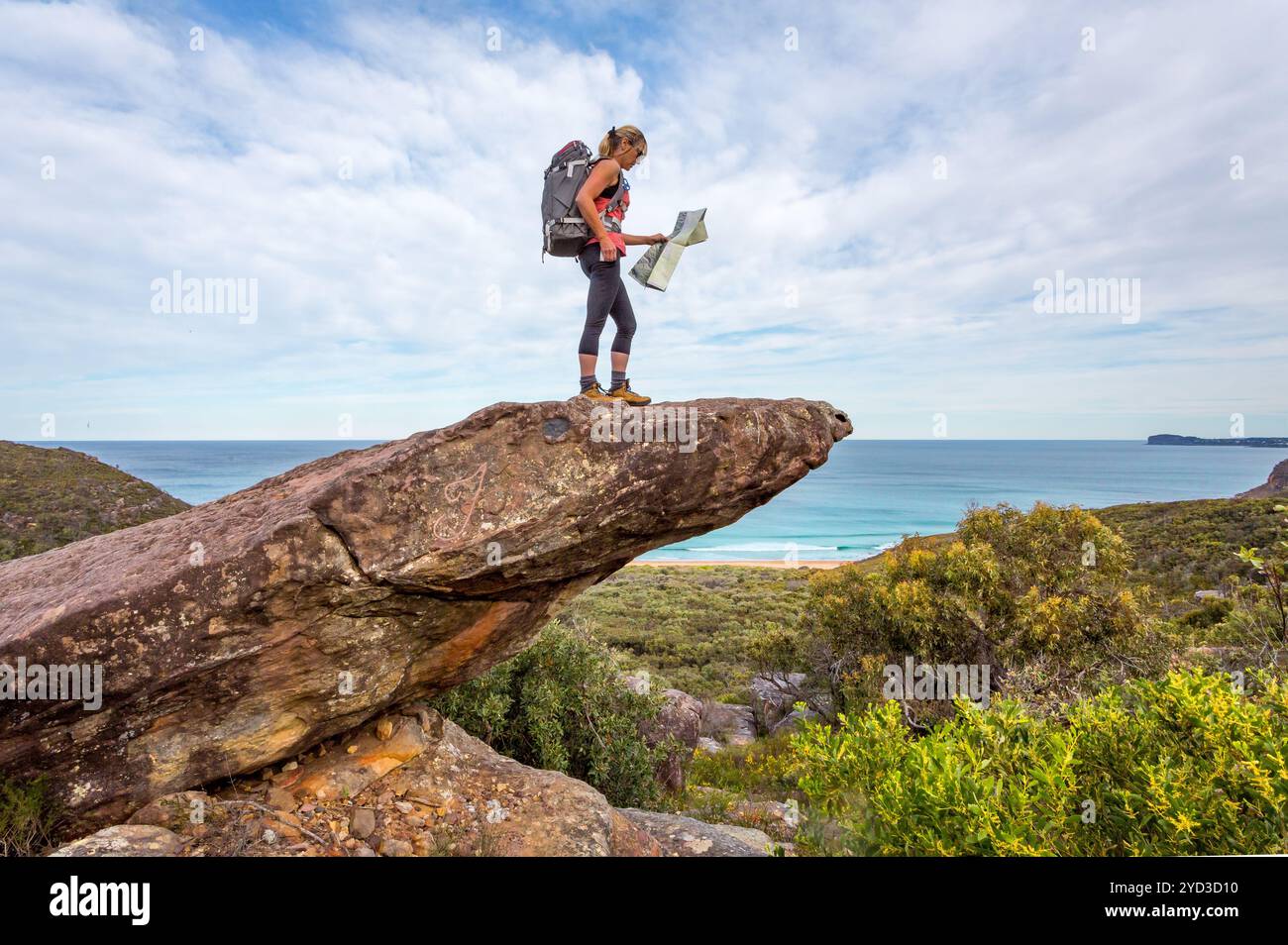 Hiker on a rock precipice holding a map Stock Photo - Alamy