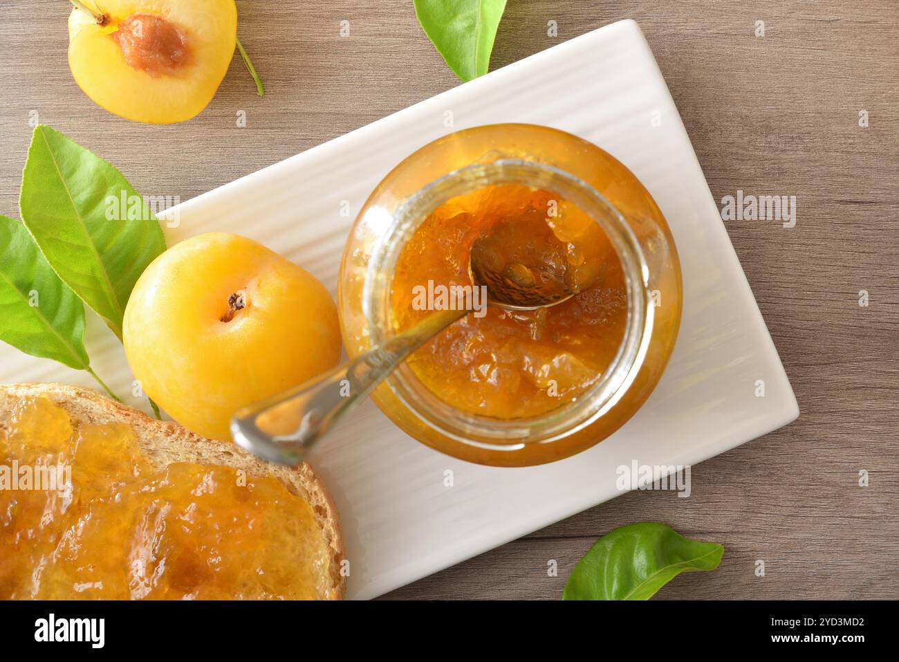 Plum jam and pieces of fruit on a white plate with a slice of bread on ...