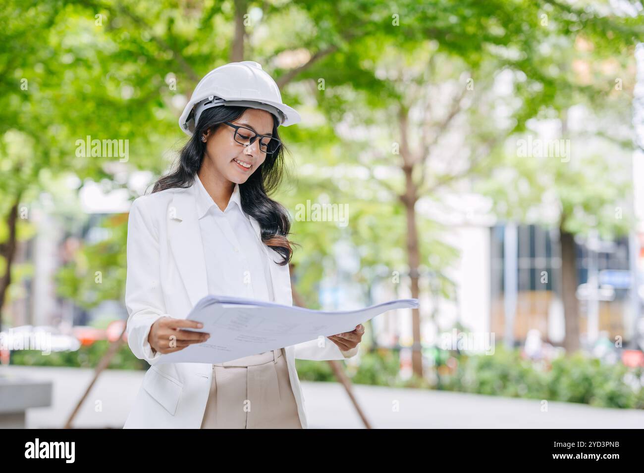Portrait smart young engineer women standing with floorplan at green ...