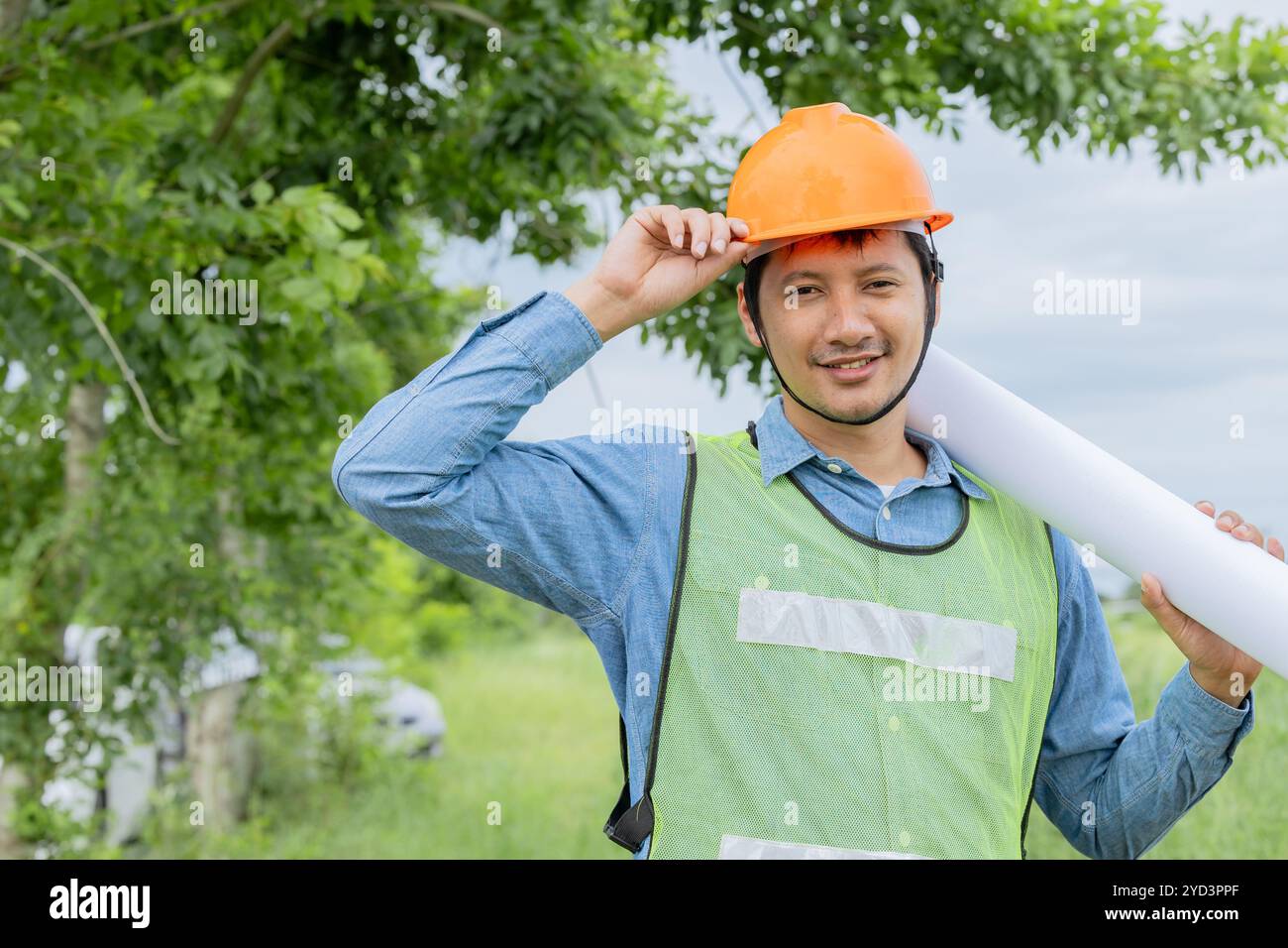 Happy Asian Engineer male with roll of blueprint enjoy outdoors with ...