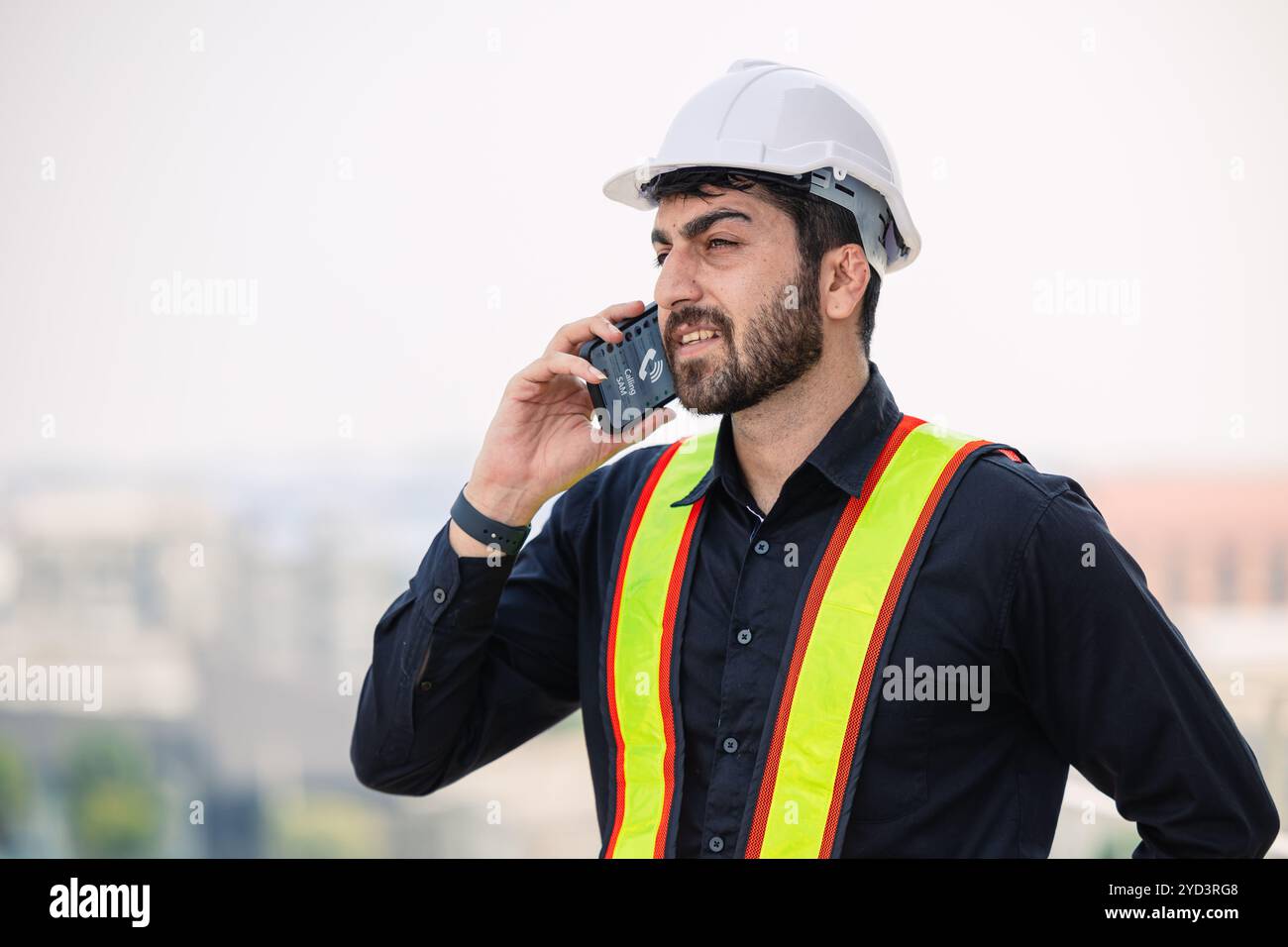 A construction worker wearing a safety helmet and vest speaks on the ...
