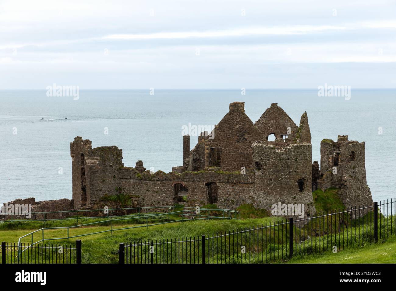 The ruins of Dunluce Castle rise on a cliff, with the ocean blending ...