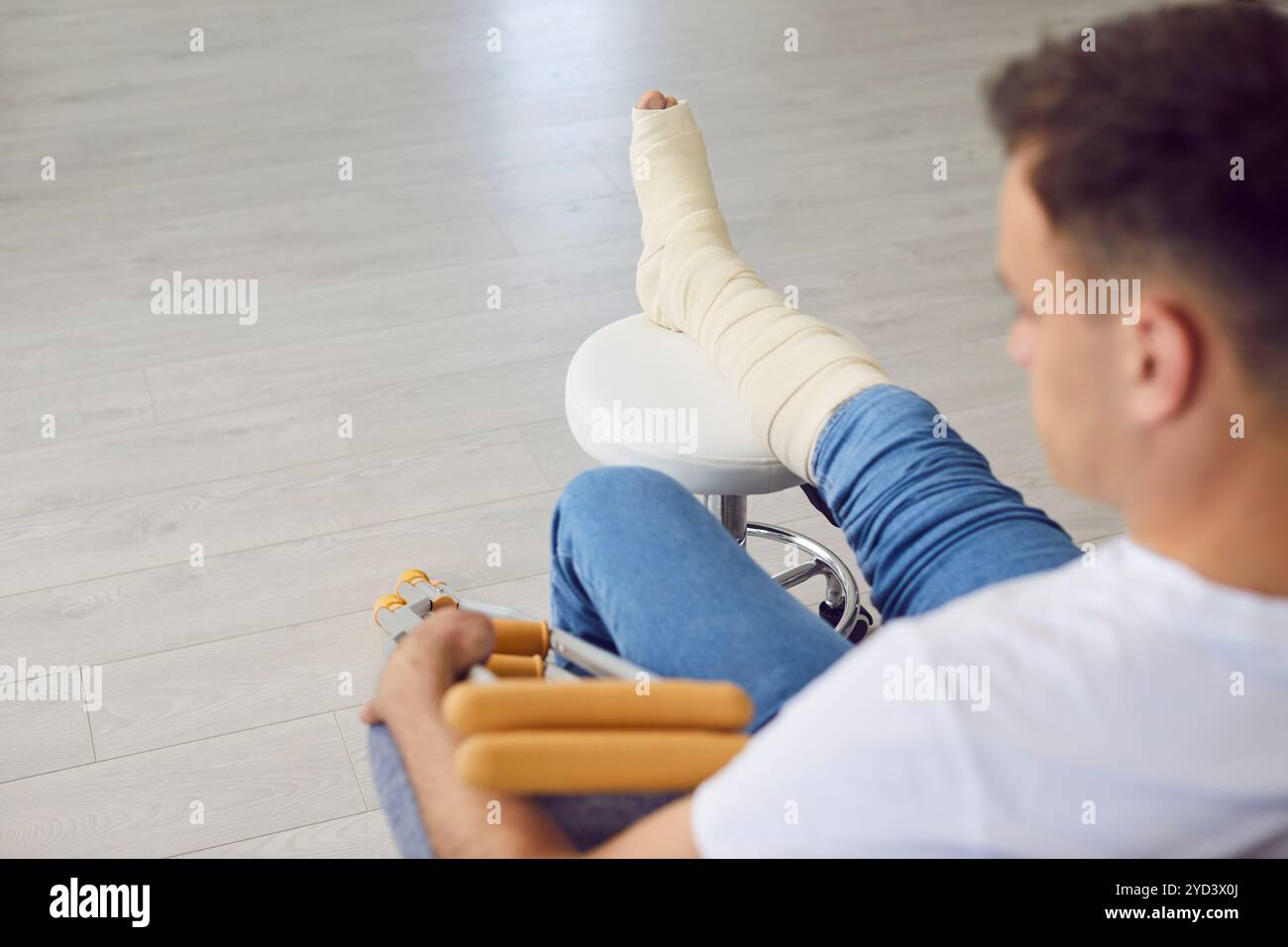 Handicapped man with leg in cast with crutch sitting on sofa at home ...