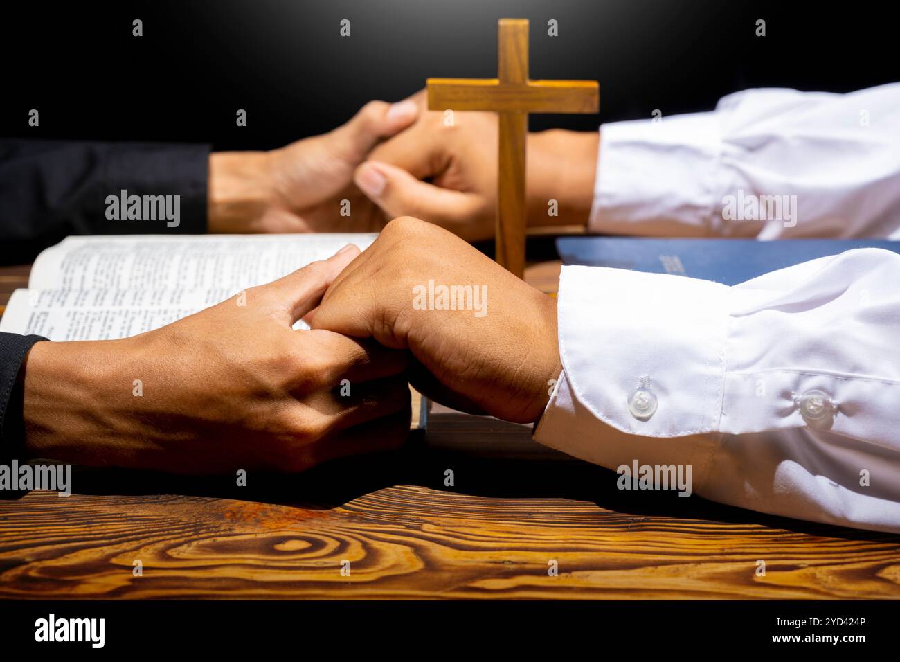 Man praying together with religion cross and on a opened holy bible ...