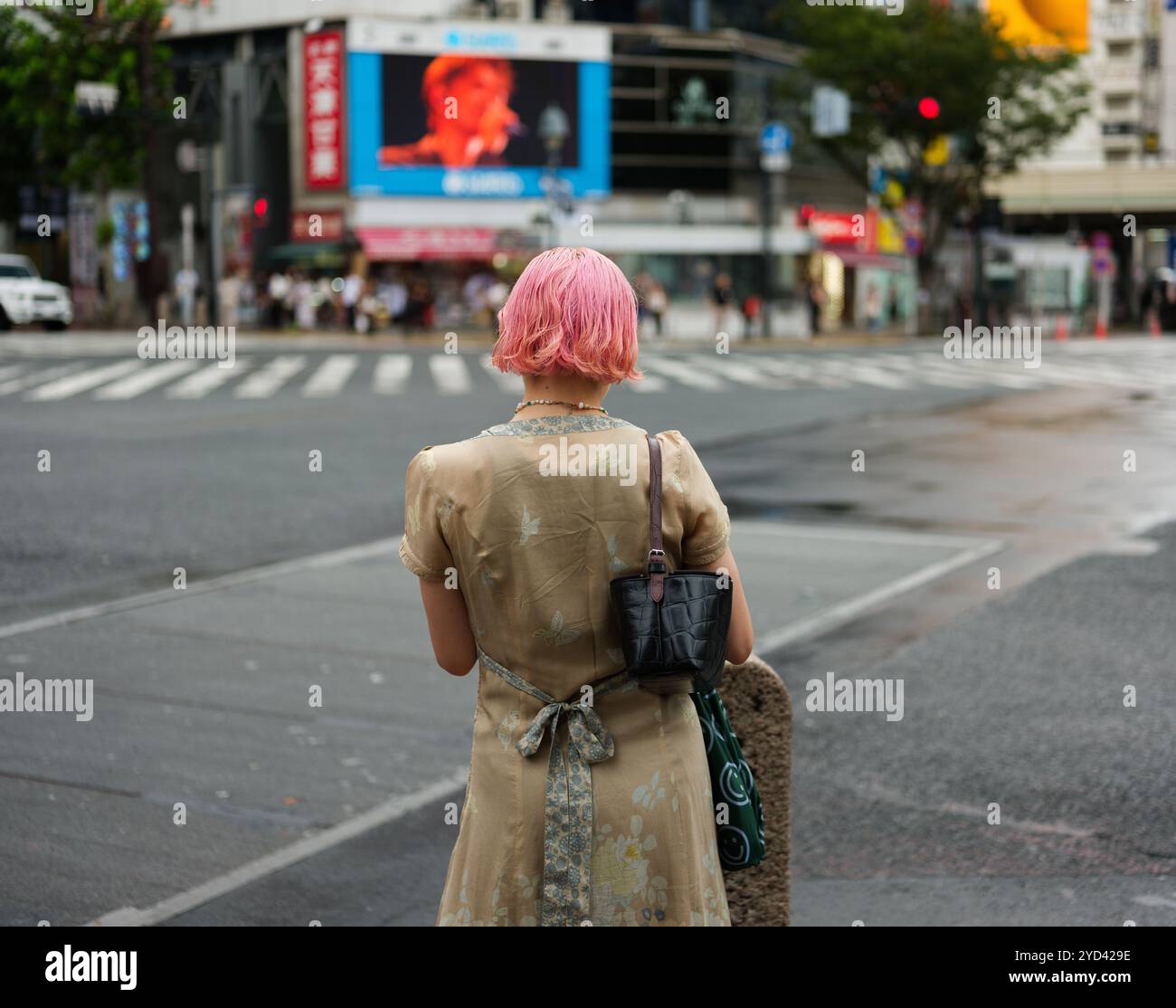 A girl with pink hair waiting to cross at the Shibuya Scramble Crossing ...