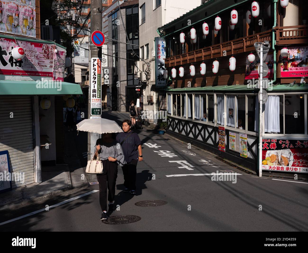 A woman using an umbrella to shield from the sun in Tokyo, Japan Stock ...