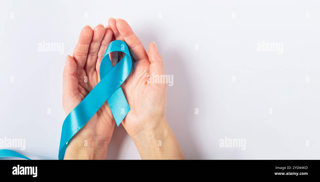 Blue cancer ribbon in woman's hand on white background Stock Photo - Alamy