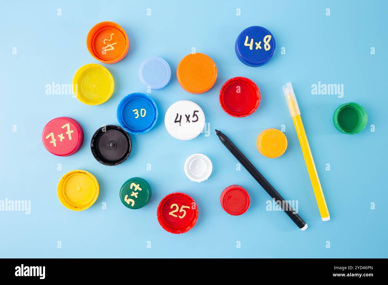 bottle caps with multiplication exercises, pencils on blue background ...
