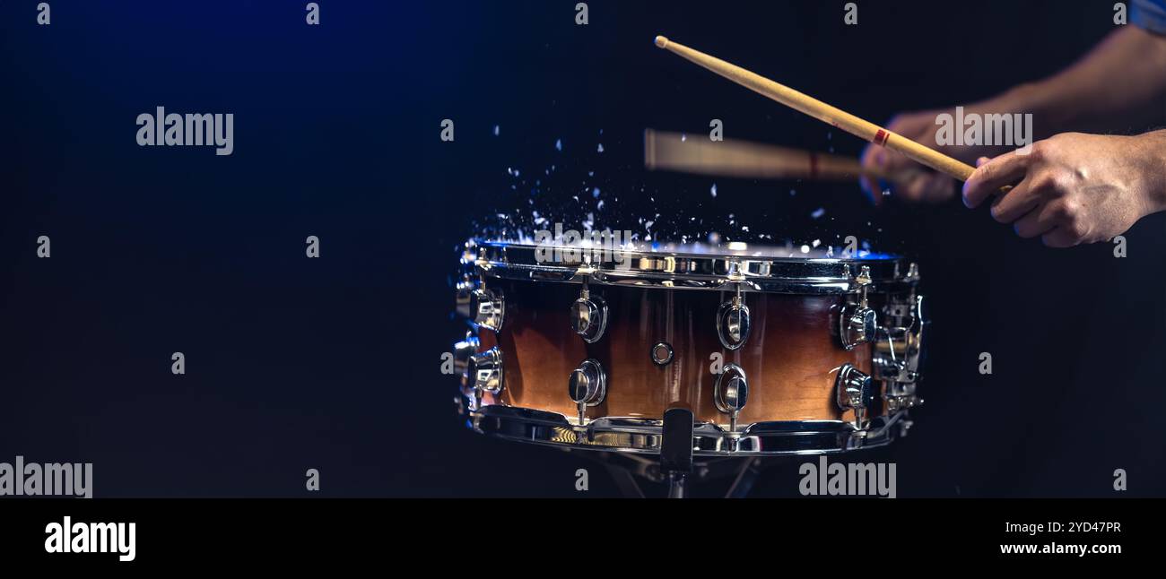 Drum sticks hitting snare drum with splashing water on black background ...