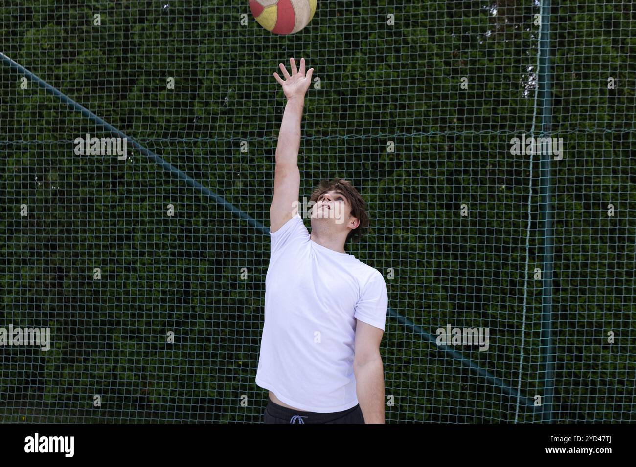 Volleyball player jumping high to serve the ball on a sand court during ...