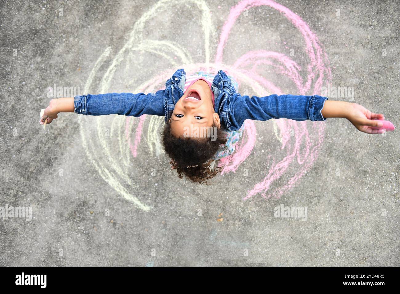 Laughing child holding chalk, arms wide, vibrant chalk drawing o Stock ...