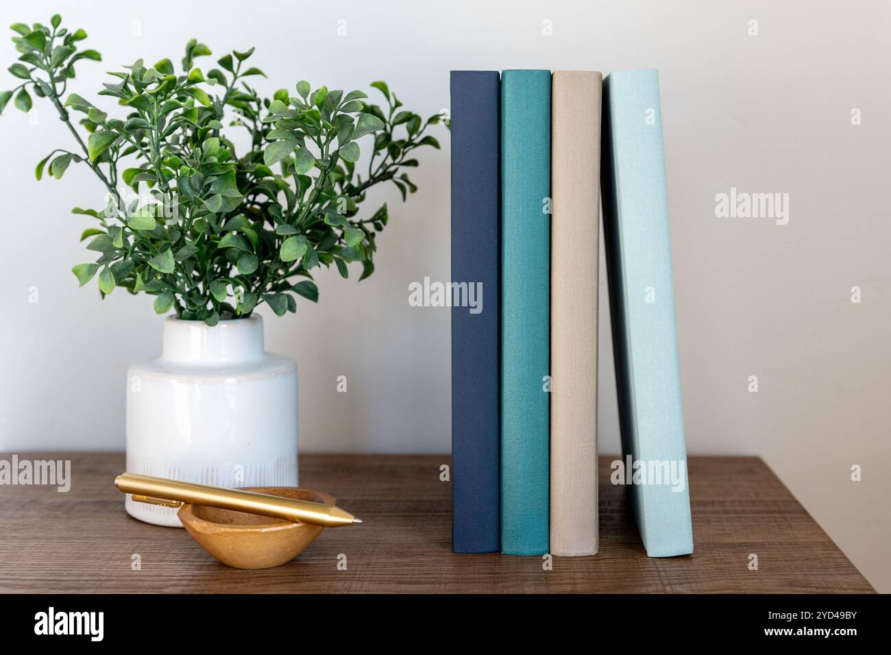 Four books standing upright on wooden table with plant Stock Photo - Alamy