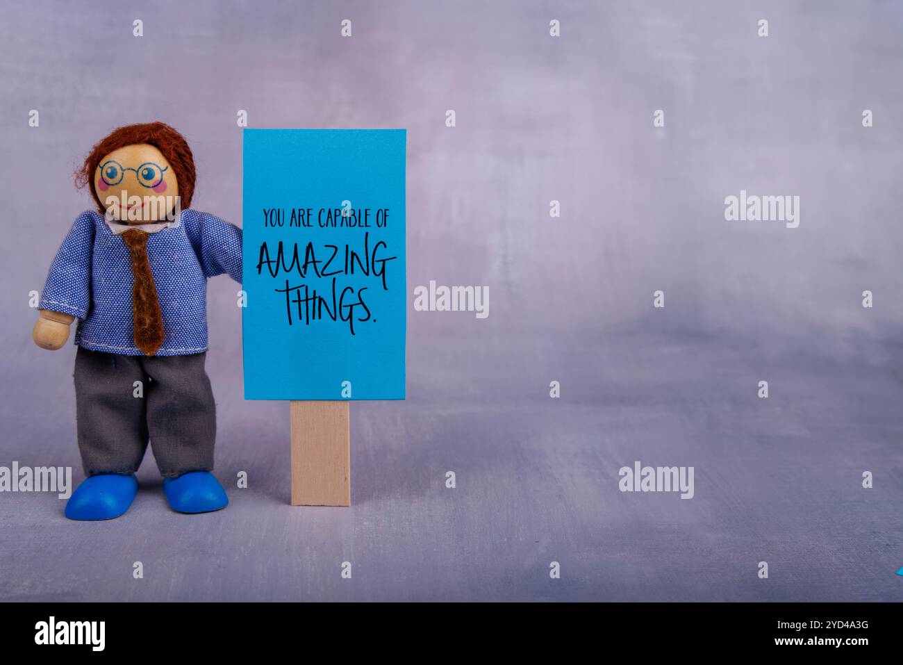 The wooden toy figure showcases a blue banner with a motivational ...