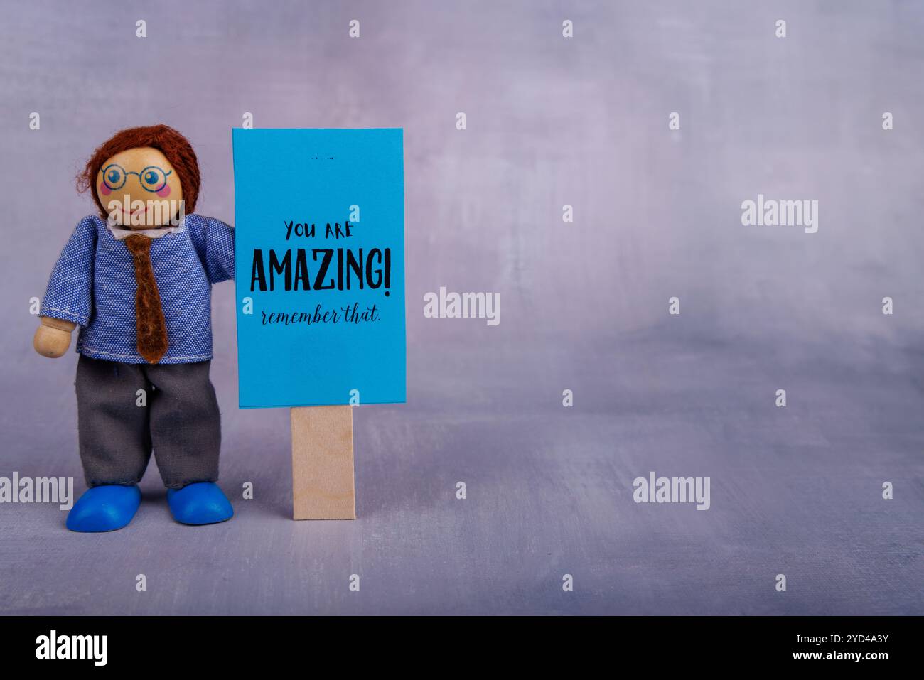 A charming wooden toy man displays a bright blue sign with a ...