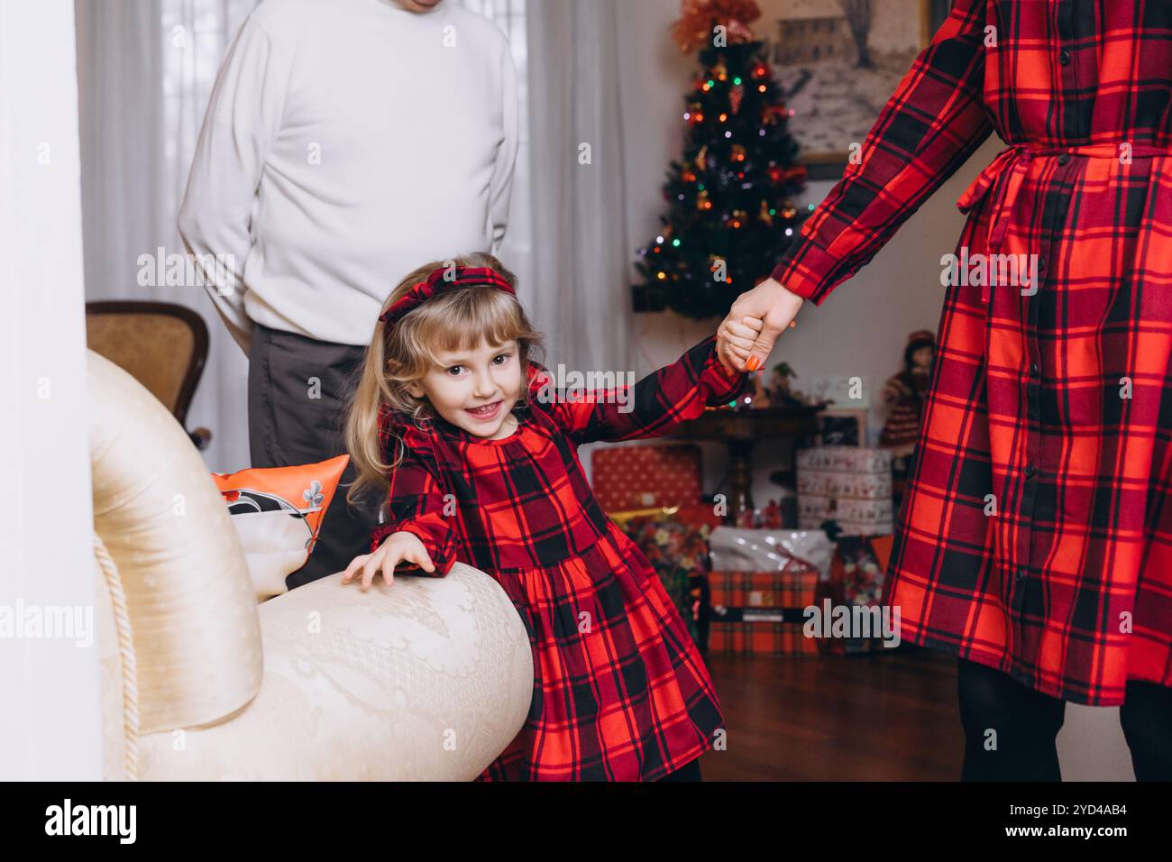 Christmas at home, little girl pulling mom's hand, playing around Stock Photo - Alamy