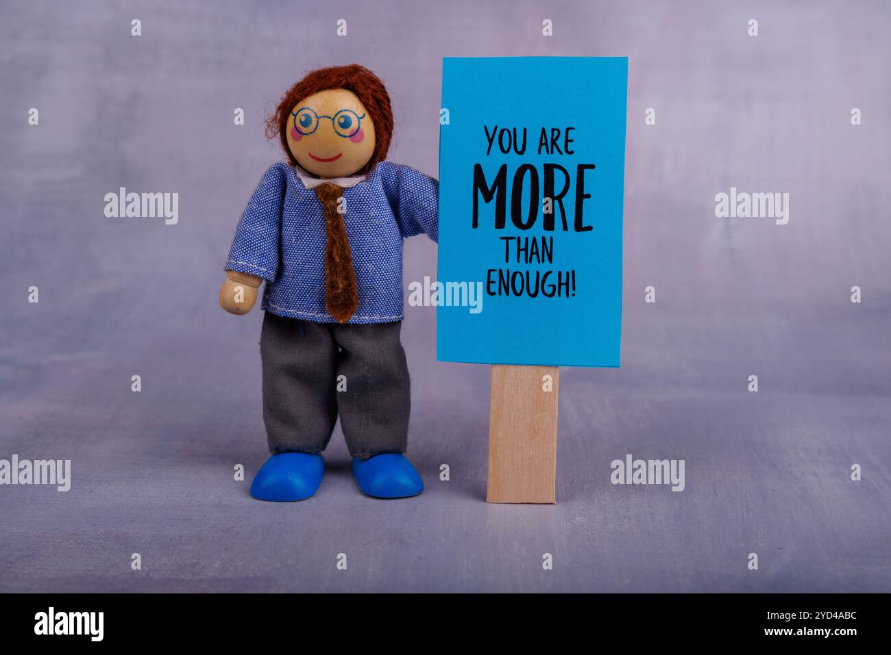 A joyful wooden toy figure showcases a blue banner with a positive ...