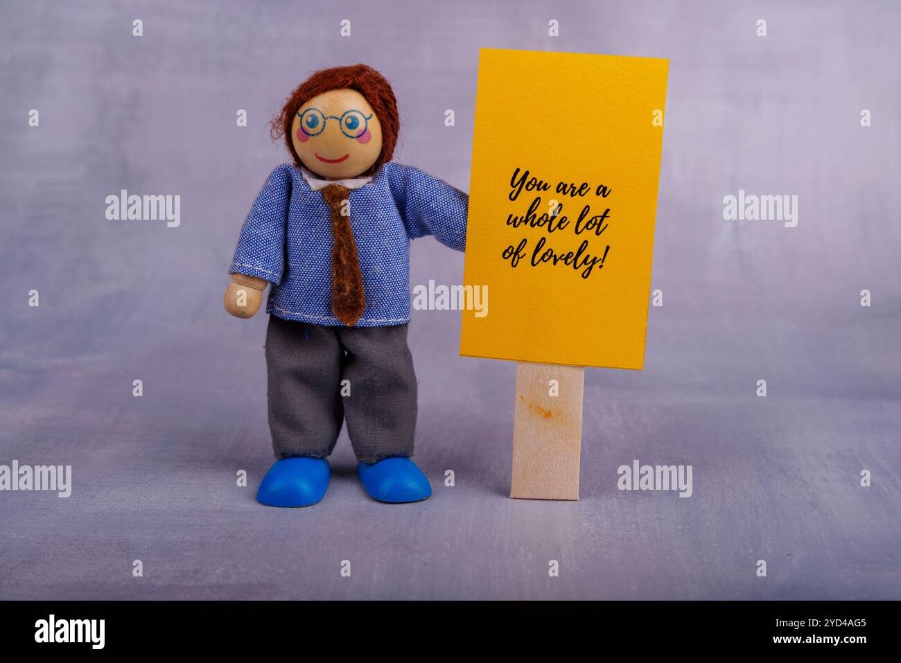 A delightful wooden toy figure holds a yellow sign featuring a positive ...
