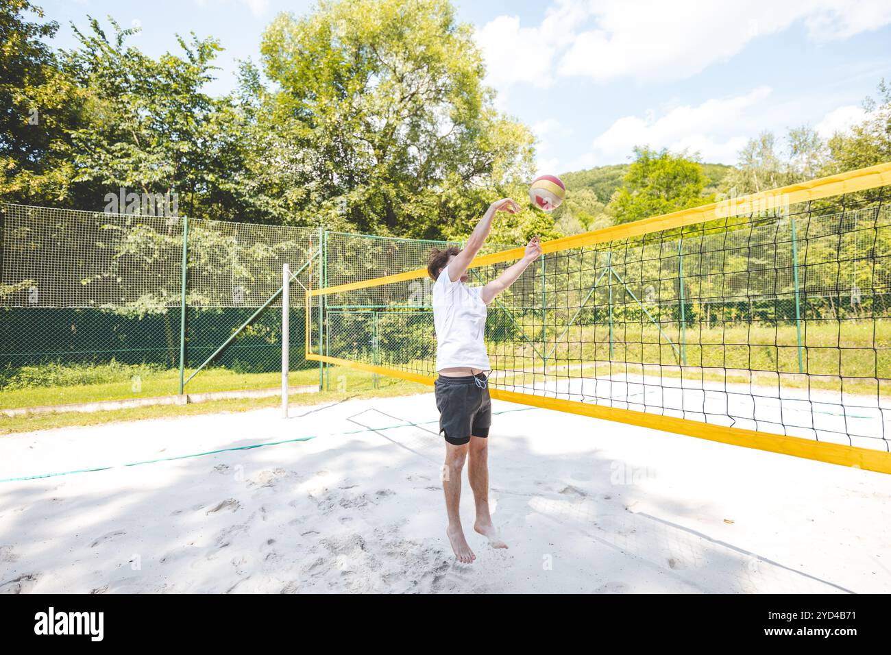 Volleyball player setting the ball on a sand court, preparing for the ...
