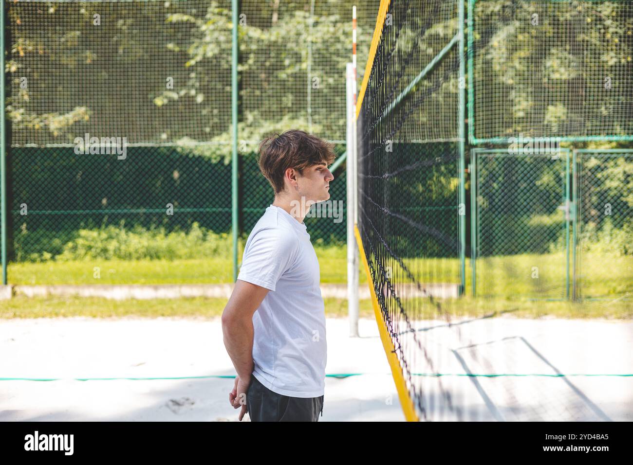 Volleyball player standing face-to-face with the net on a sand court ...
