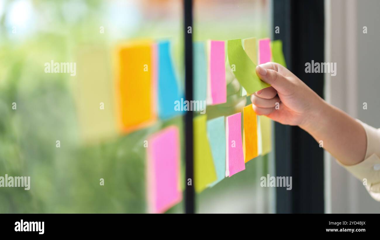 Creative startup putting ideas on sticky note at modern office Stock ...