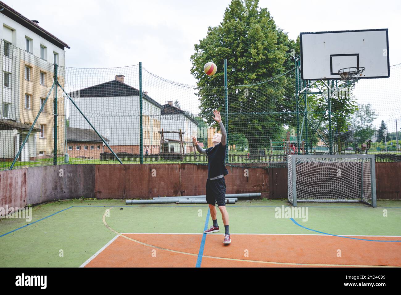 Volleyball player is serving on a hard court during an outdoor game ...