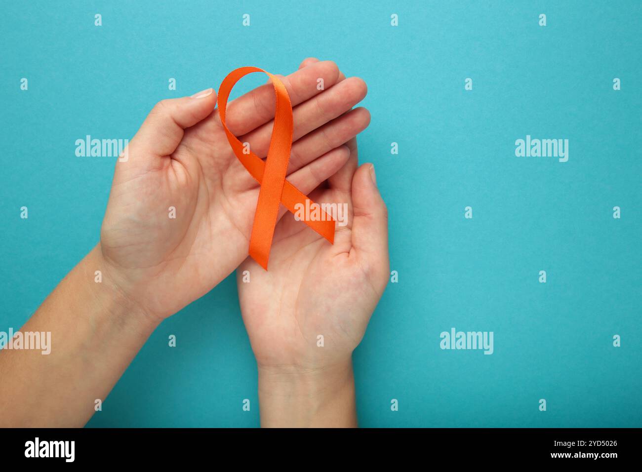 Hands holding orange color ribbon on blue background. Kidney Cancer ...
