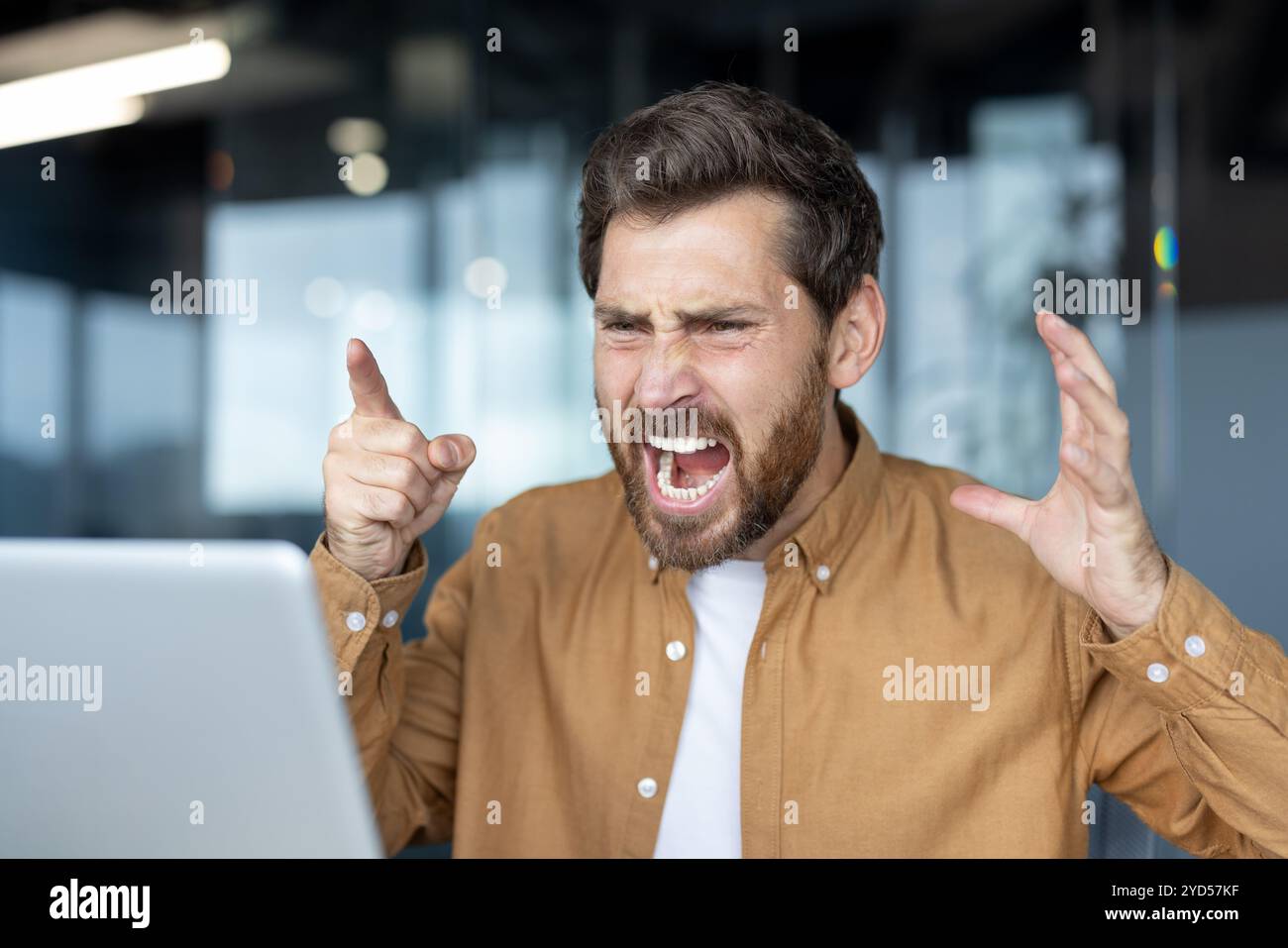 Frustrated businessman yelling at laptop during video call. Intense ...