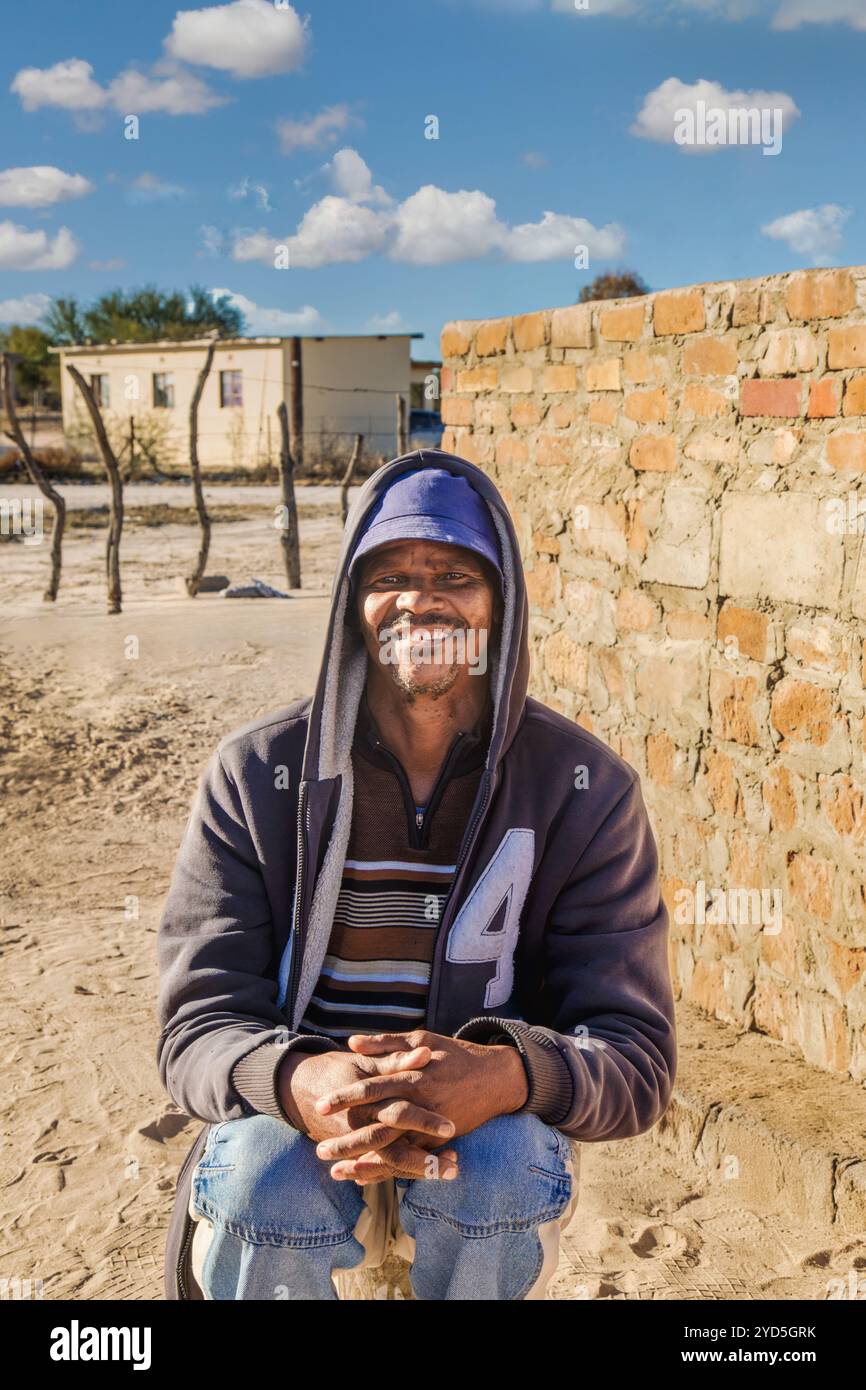 happy village african single man sitting on the ground in the yard ...