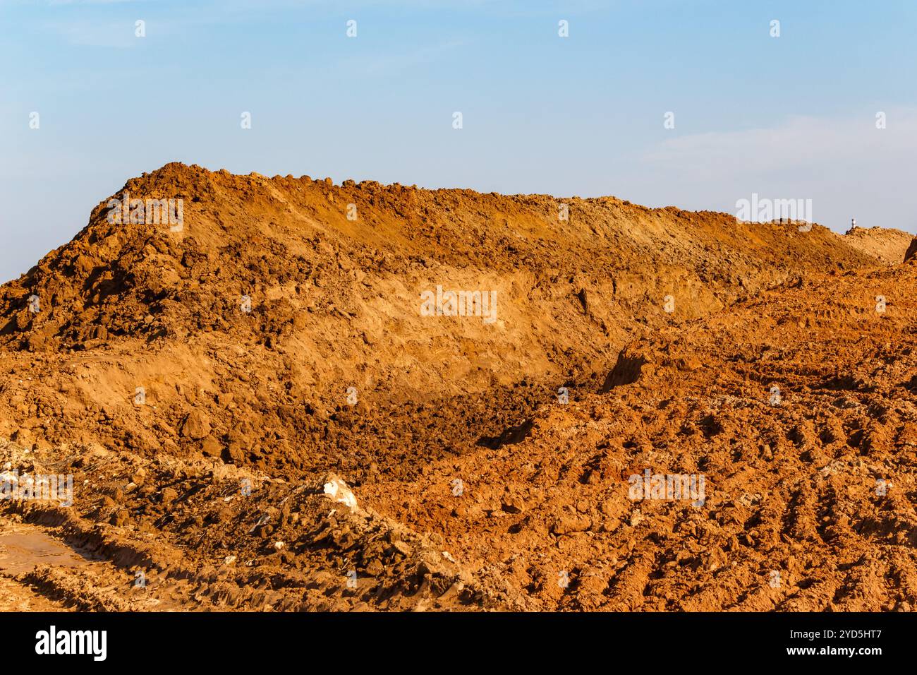 A plot of land dug up by an excavator, a mound of clay soil after ...