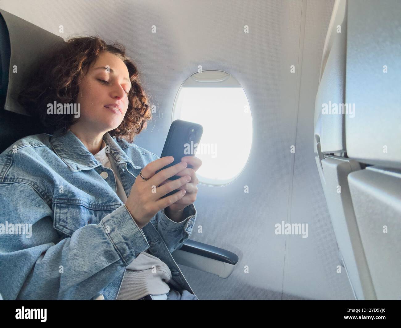 Passenger woman is flying in plane. Girl using phone sitting by ...