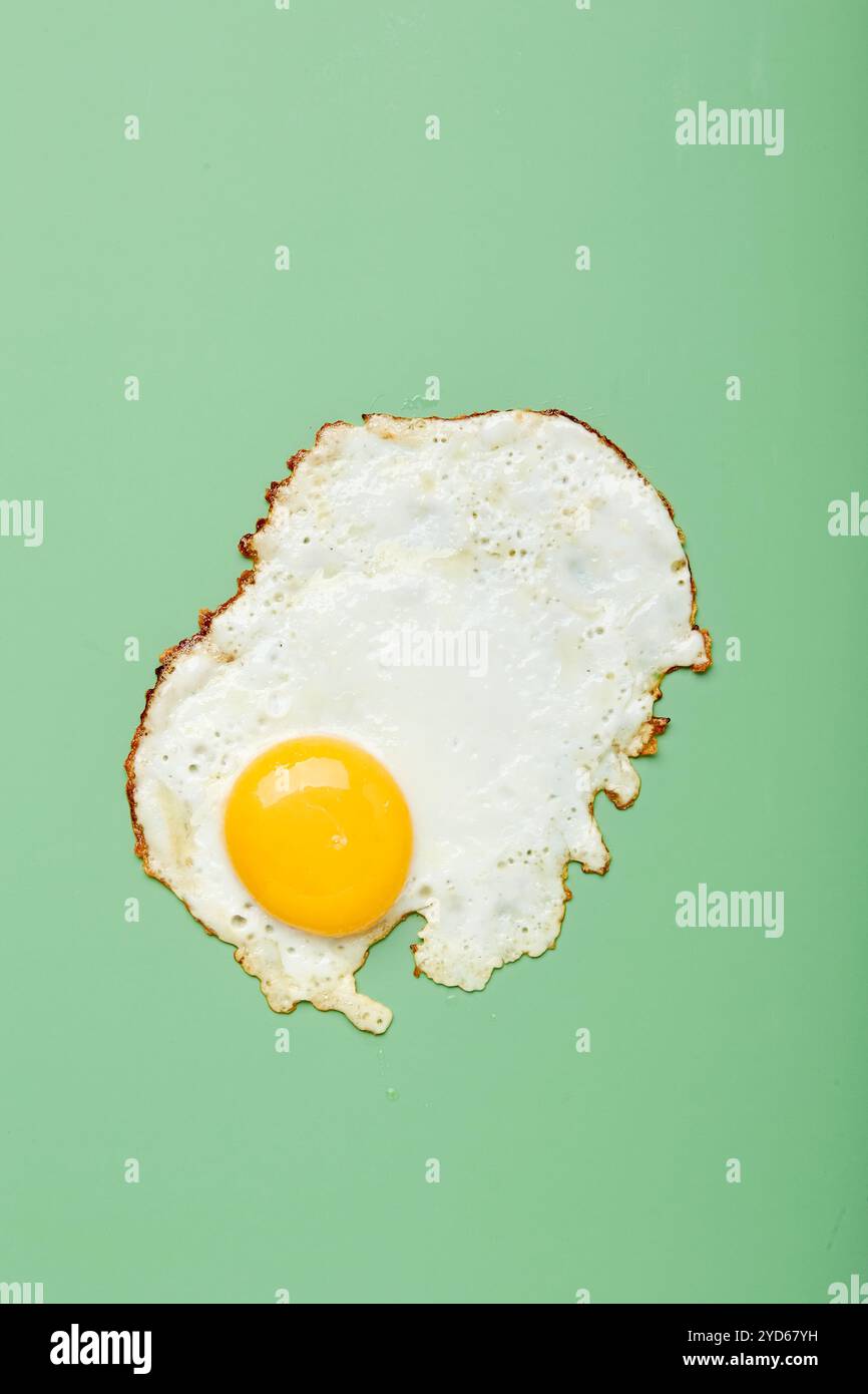 Fried egg with bright yolk on green background Stock Photo - Alamy