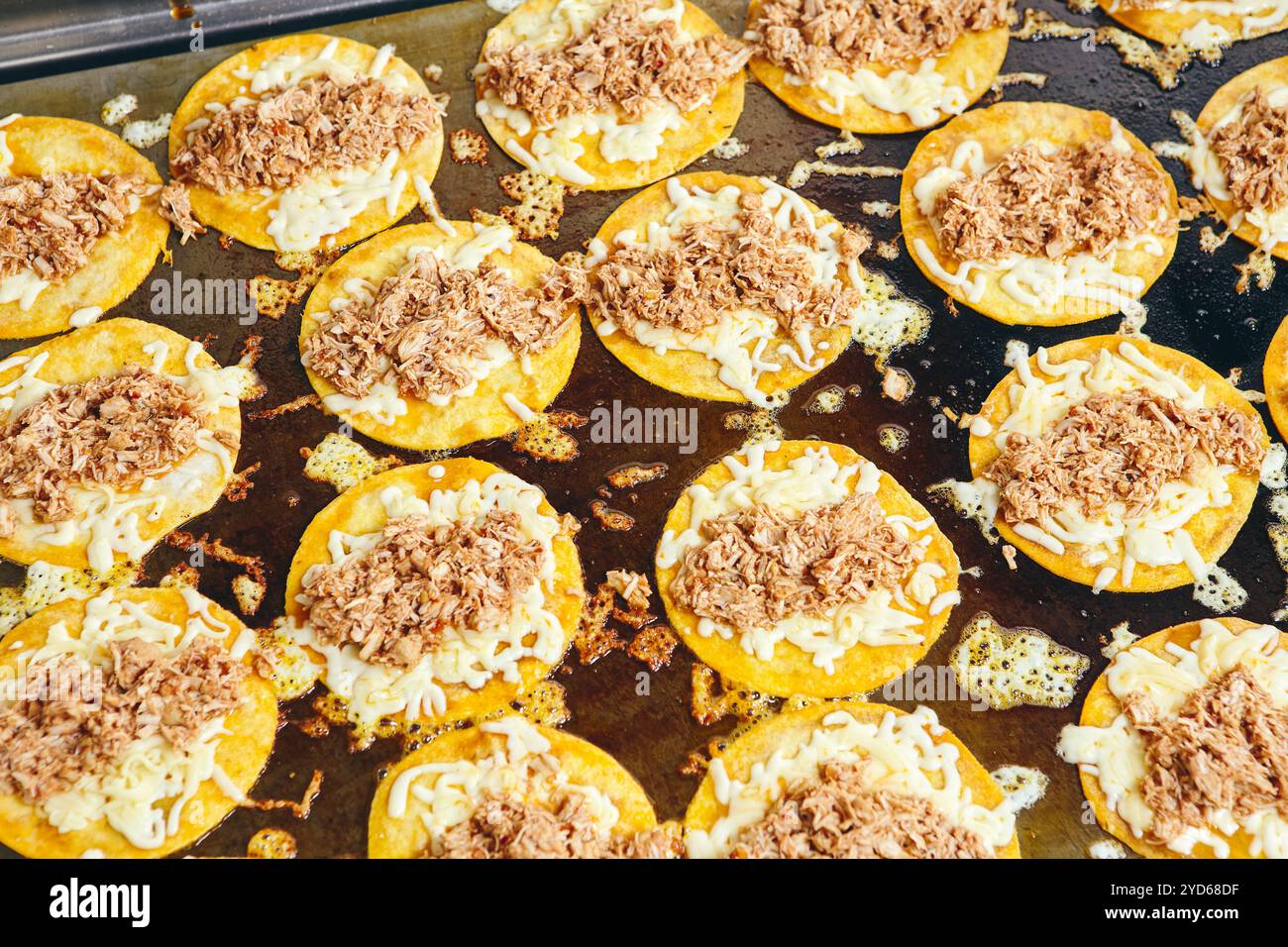 Frying tacos tortillas with cheese and meat on griddle in professional ...