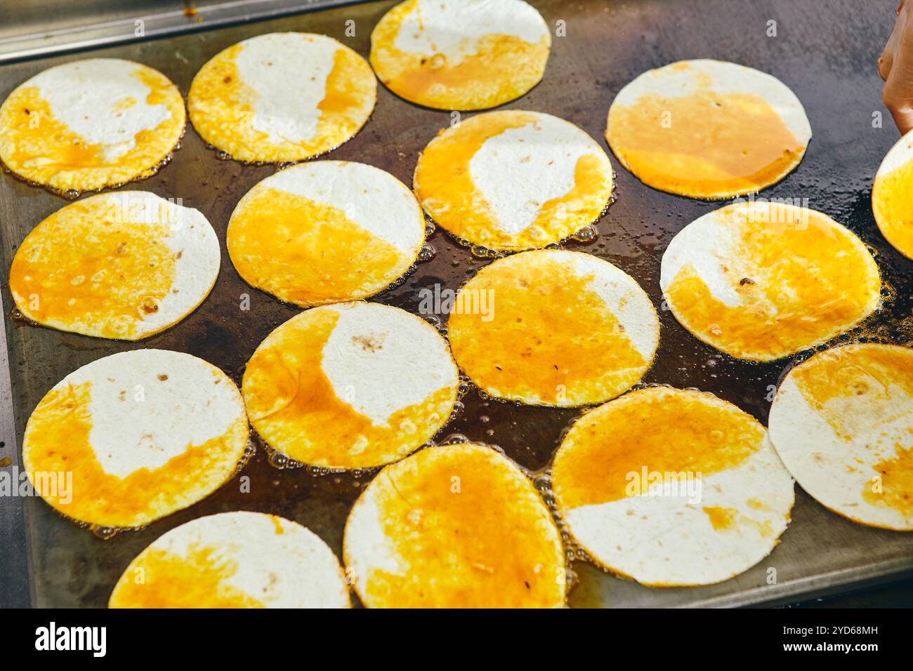 Tacos tortillas preparation on griddle in professional kitchen in ...