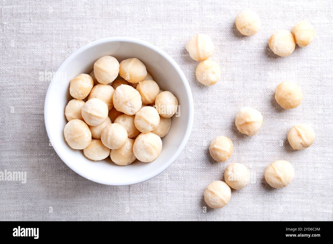 Macadamia nuts, roasted and salted, in a white bowl on linen fabric ...