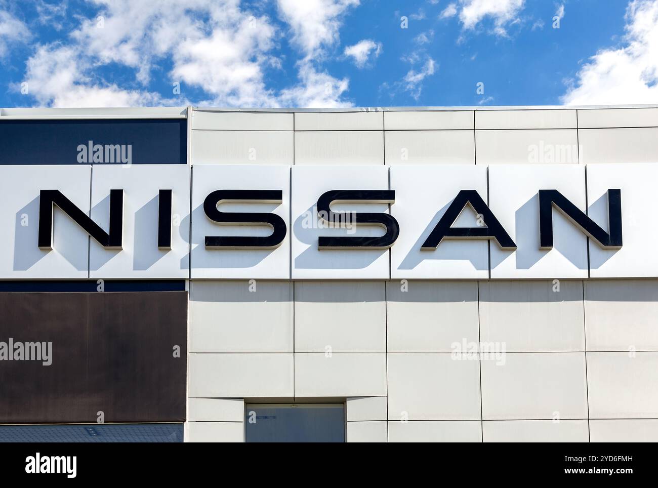 Official dealership sign of Nissan on the wall of the office building ...