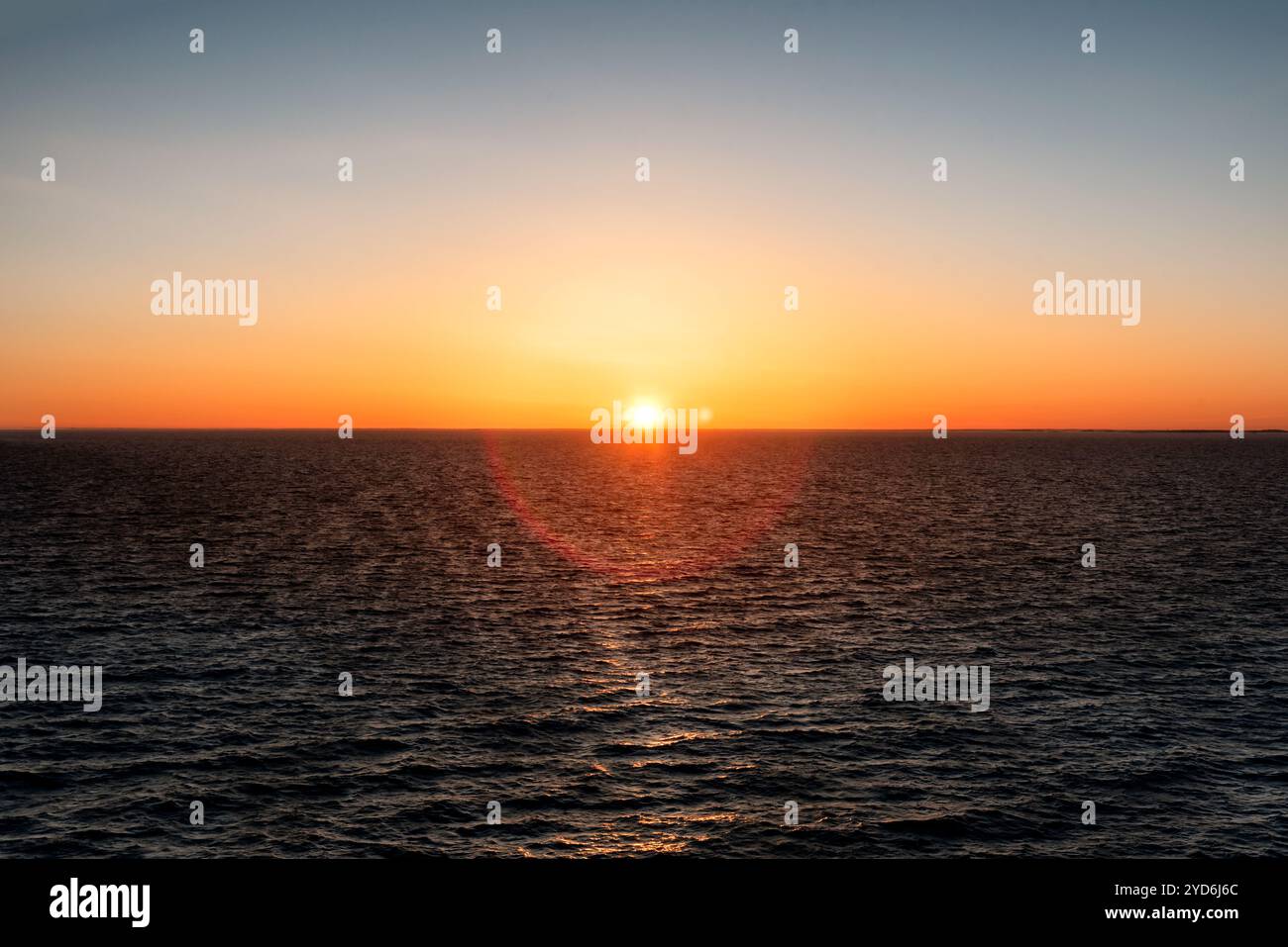 Baltic sea at sunset. Clear sky with glowing golden sun, reflections in ...