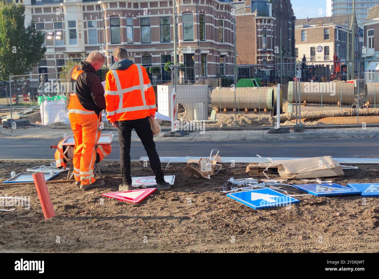 Two workers confer at the site of a roundabout under construction, road ...