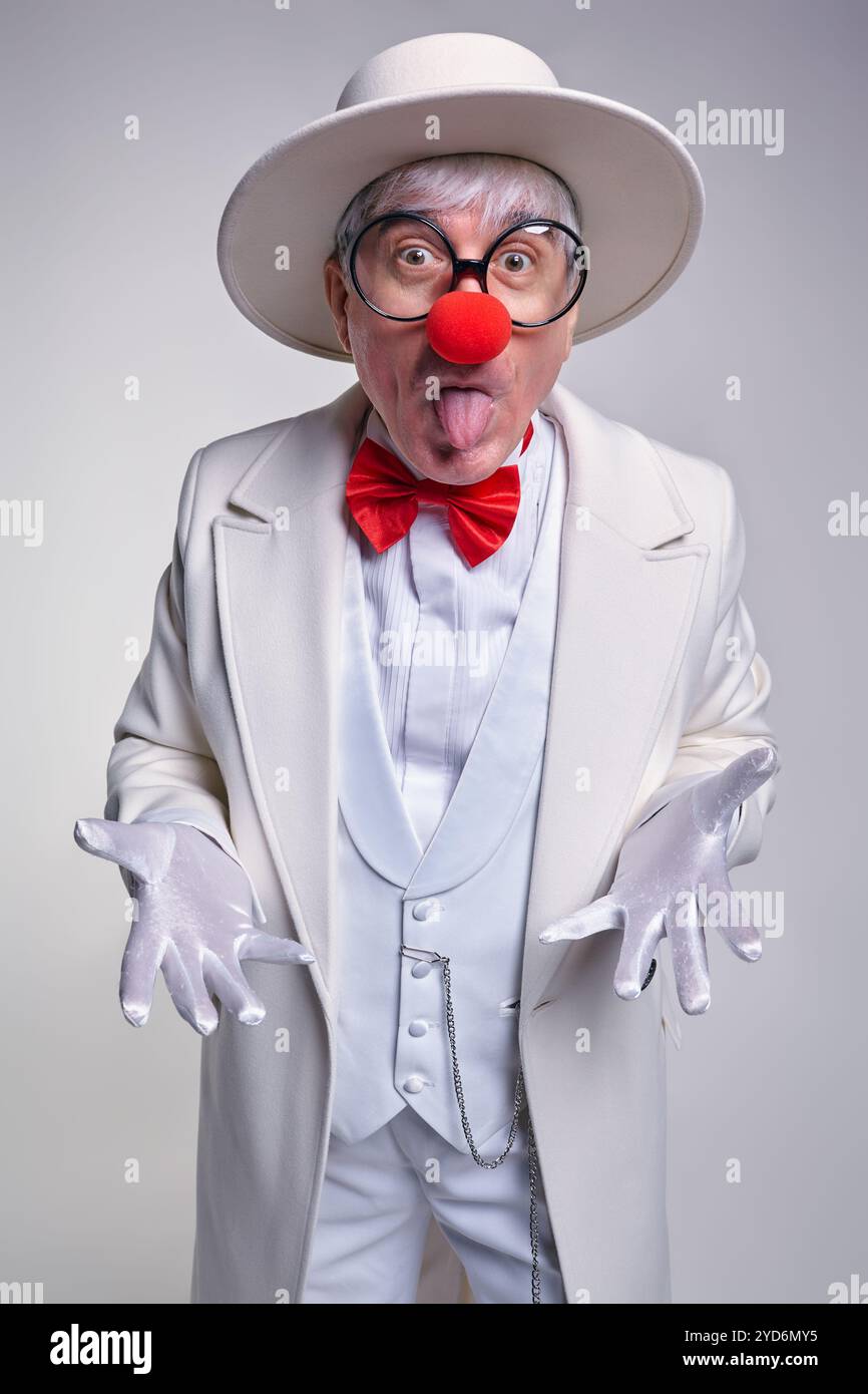 The clown sticks out his tongue and extends his gloved hands forward ...
