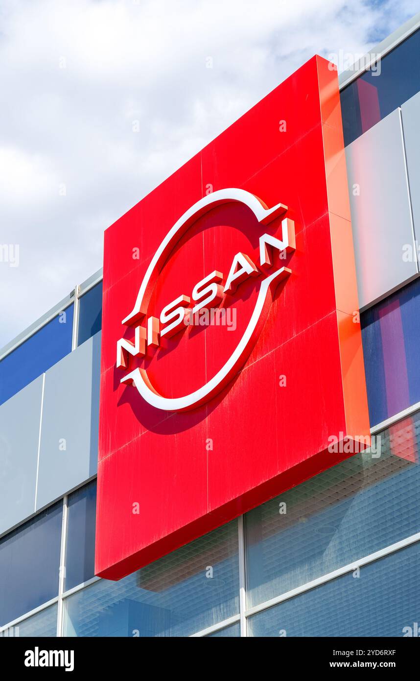 Official dealership sign of Nissan on the wall of the office building ...