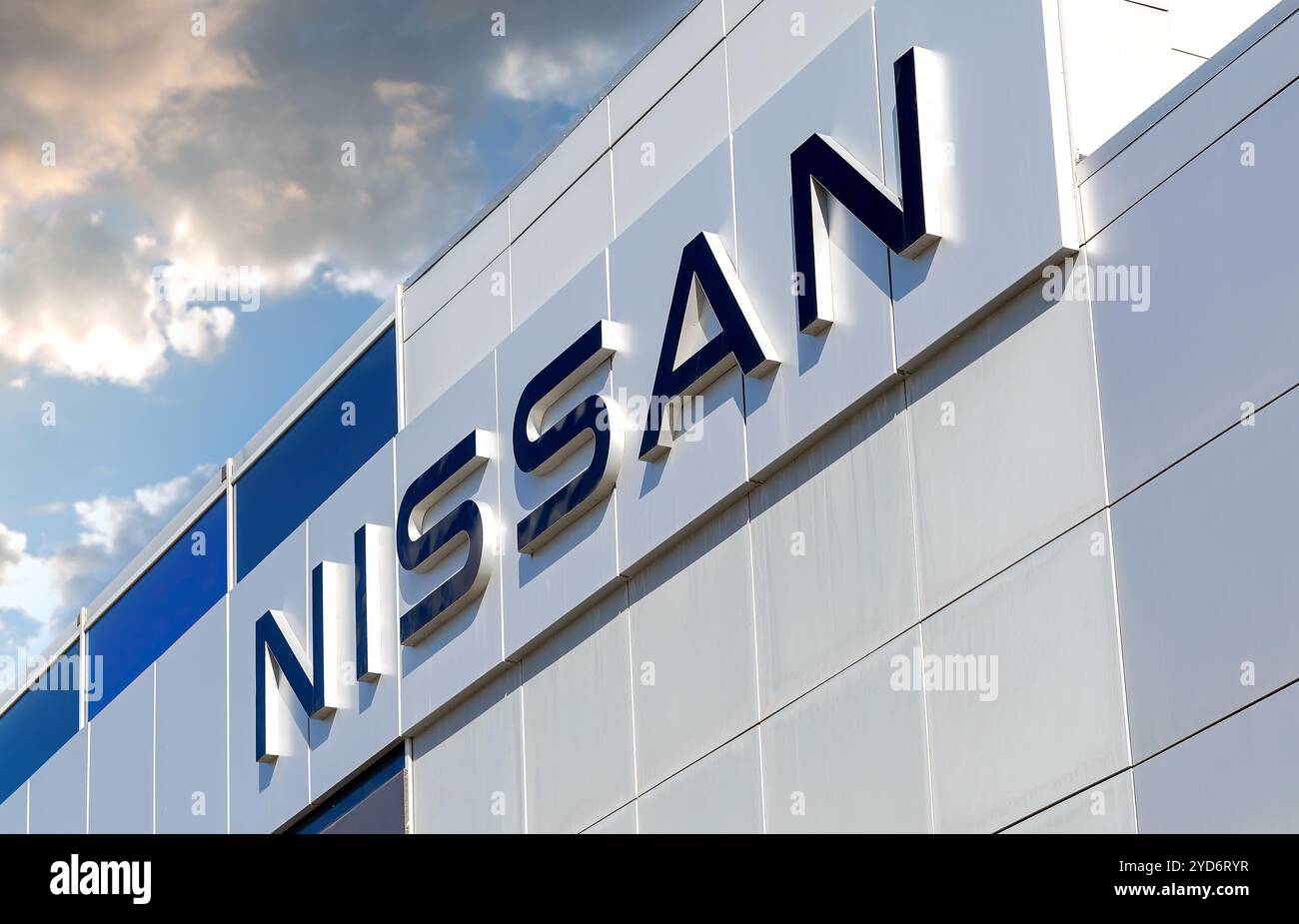 Official dealership sign of Nissan on the wall of the office building ...