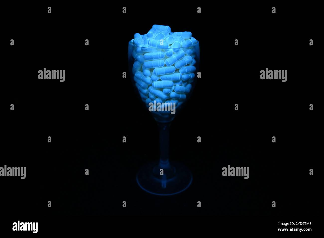 A wine glass full of tablets glowing under UV light Stock Photo - Alamy