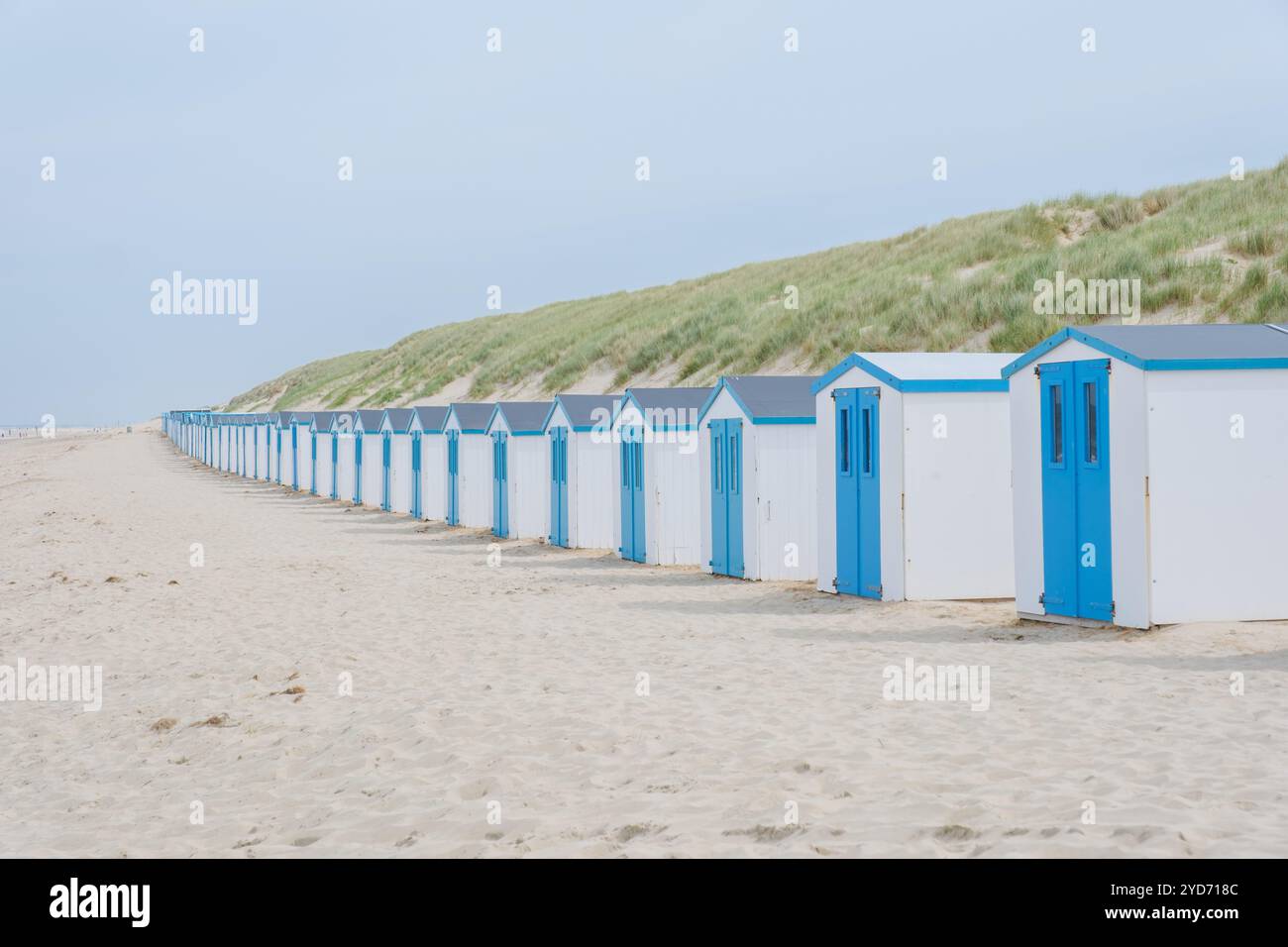 A peaceful scene unfolds as a row of charming blue beach huts stand ...