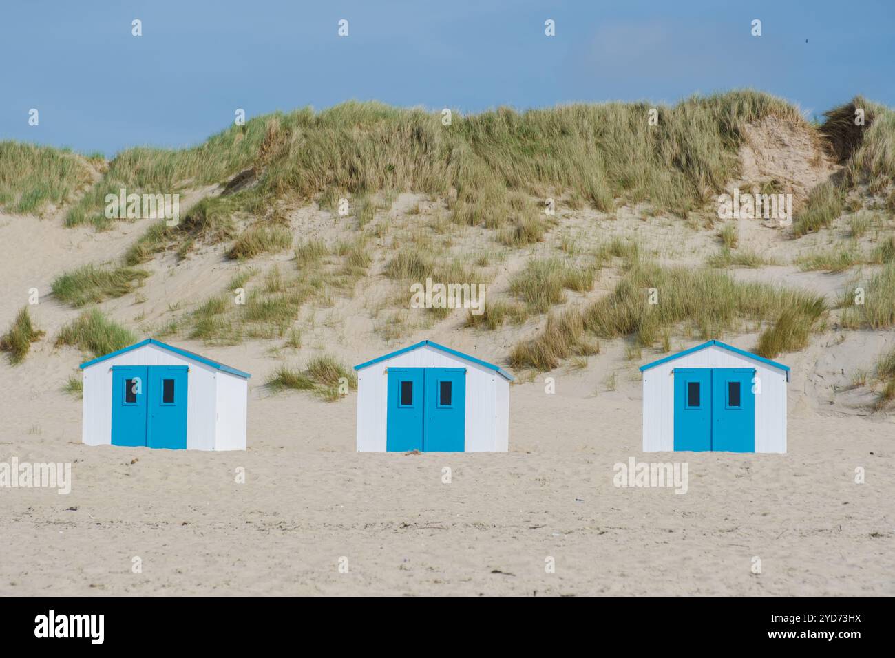 Beach huts painted in a rainbow of colors line the sandy shore on Texel ...