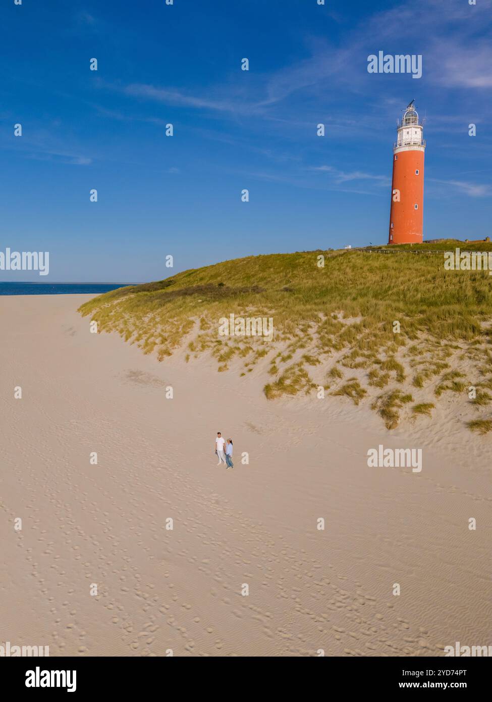 A majestic lighthouse stands tall on a sandy beach, guiding ships with ...