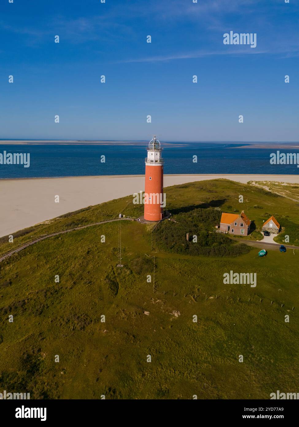 A majestic lighthouse stands tall on a green hill in Texel, Netherlands ...