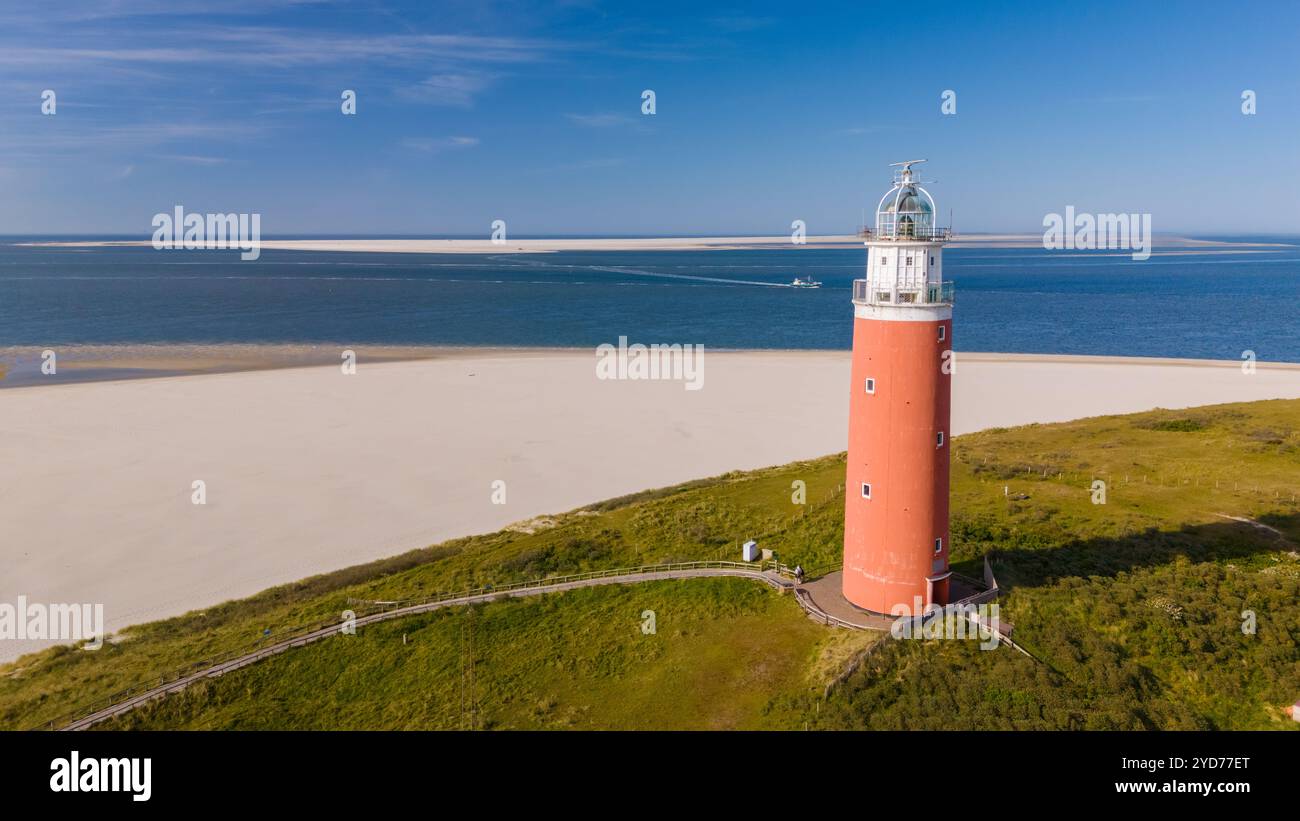 A majestic lighthouse stands tall on a sandy beach, guiding ships to ...