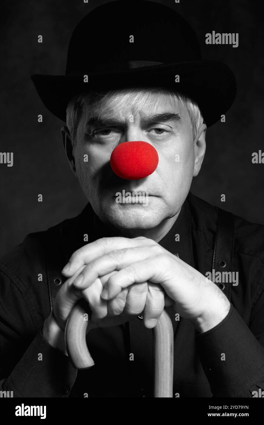 Dramatic selective color portrait of a clown against a dark background ...