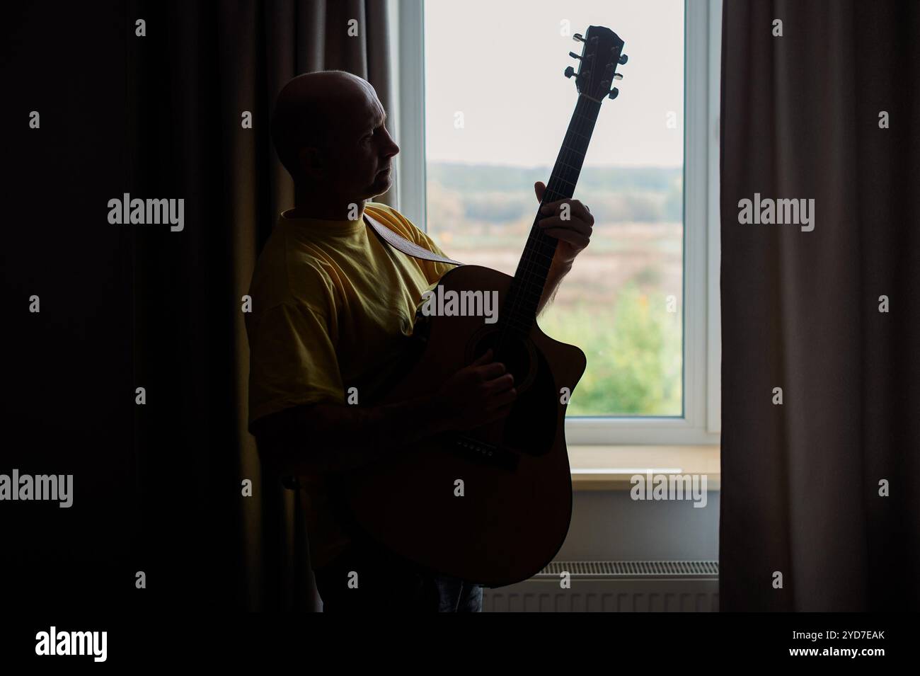 Silhouette of guitarist paying a acoustic guitar against window. Man ...
